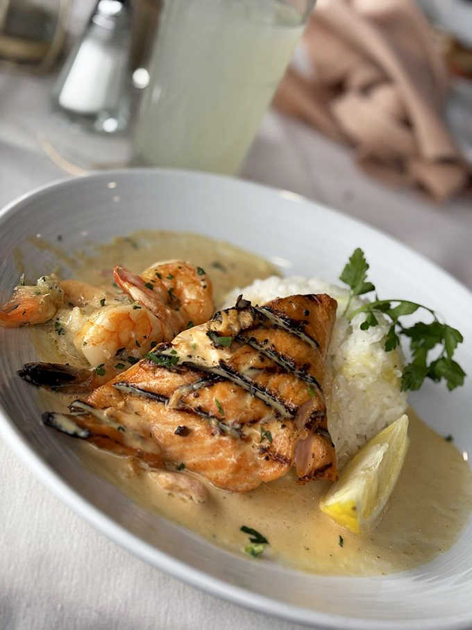 Perfectly grilled salmon swimming in buttery sauce with plump shrimp companions. This plate doesn't just feed you&mdash;it transports you.