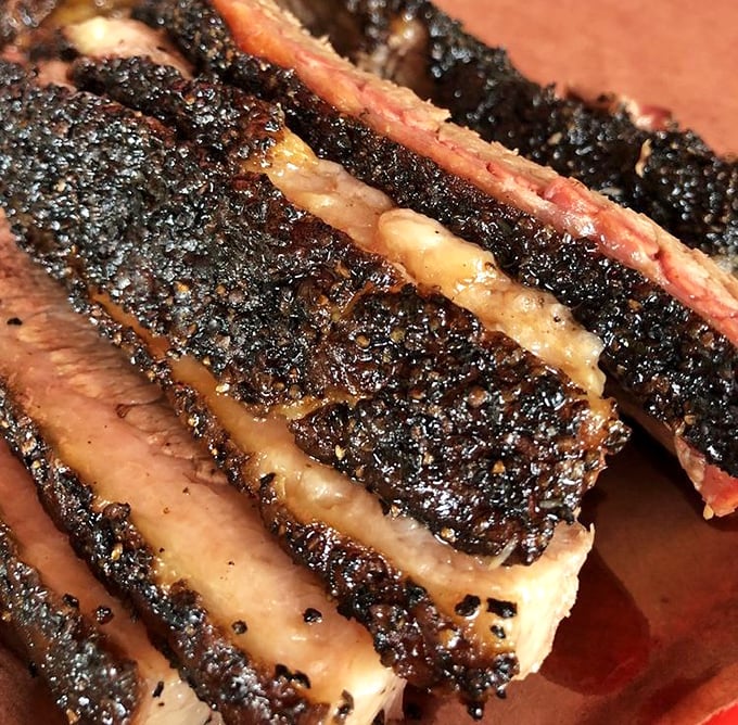 Behold the holy grail of Texas barbecue: brisket with a peppery bark so perfect it should be hanging in a museum. That smoke ring is basically a halo.