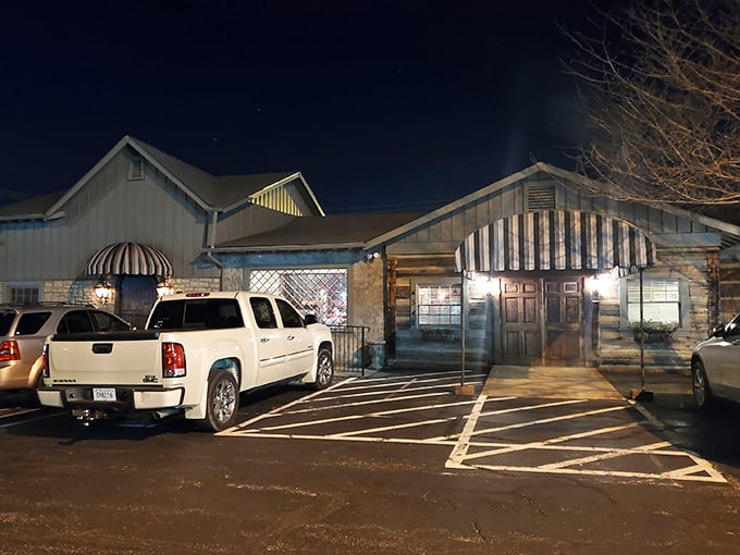 Hermitage Steak House glows in the evening light, a rustic cabin that beckons hungry travelers with promises of sizzling perfection.