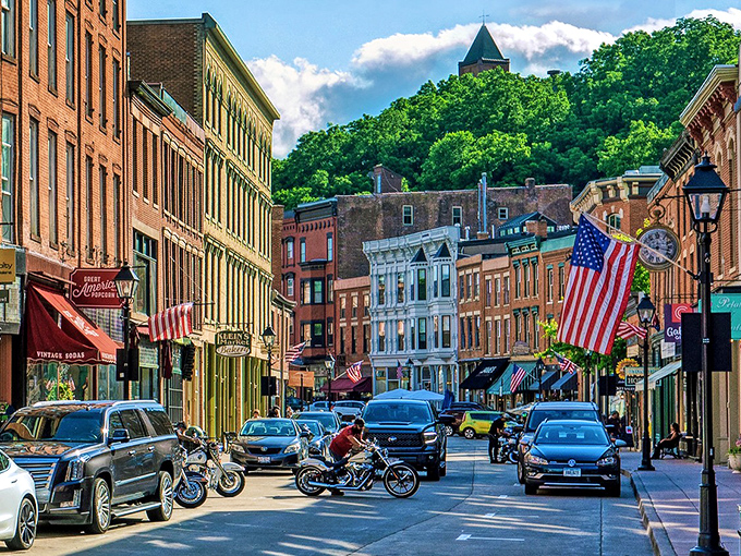 Galena's postcard-perfect main street winds through historic buildings with American flags proudly displayed, all nestled beneath green hillsides.