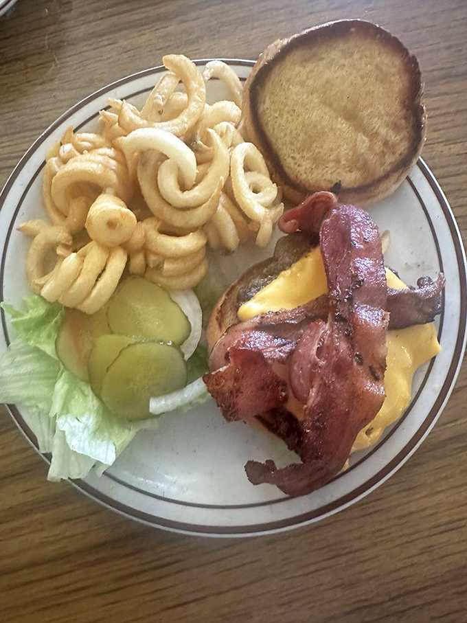 The classic American cheeseburger gets the royal treatment with crispy bacon, melty cheese, and those gloriously curly fries that defy gravity.