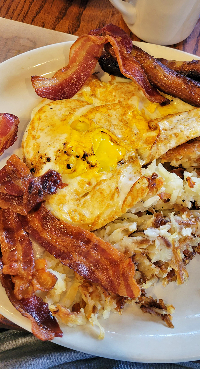 The holy trinity of breakfast: perfectly crisp bacon, sunny-side-up eggs, and hash browns with that ideal crisp-to-tender ratio. Morning salvation on a plate.
