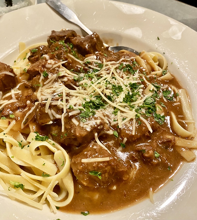 The beef stroganoff arrives like a savory lullaby&mdash;tender chunks of beef swimming in rich gravy over pasta, sprinkled with enough parmesan to make an Italian grandmother nod approvingly.