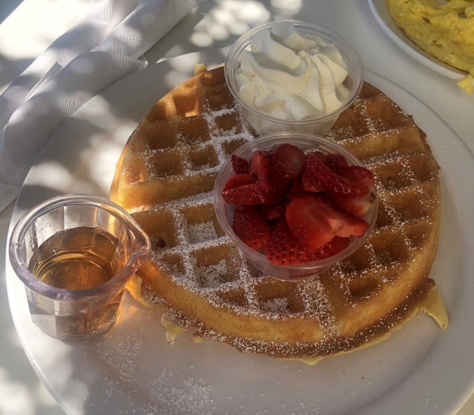This Belgian waffle isn't just breakfast, it's architecture&mdash;golden, crisp infrastructure supporting delicate strawberries and a cloud of whipped cream.