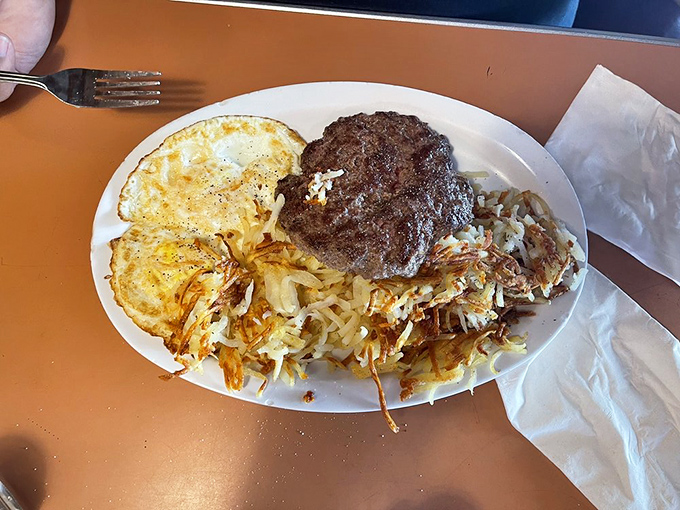 The breakfast trinity: perfectly scrambled eggs, crispy bacon, and those legendary hash browns. A holy alliance of morning deliciousness on a single plate.