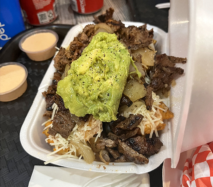 Carne asada fries - where protein meets potato in a magnificent marriage topped with a generous avocado crown. This is comfort food elevated to art form.