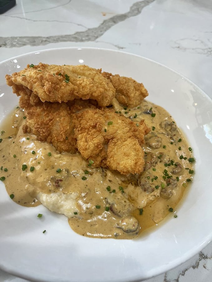 The star attraction: perfectly crispy catfish perched atop creamy grits with a savory sauce that would make your grandmother both proud and slightly jealous.