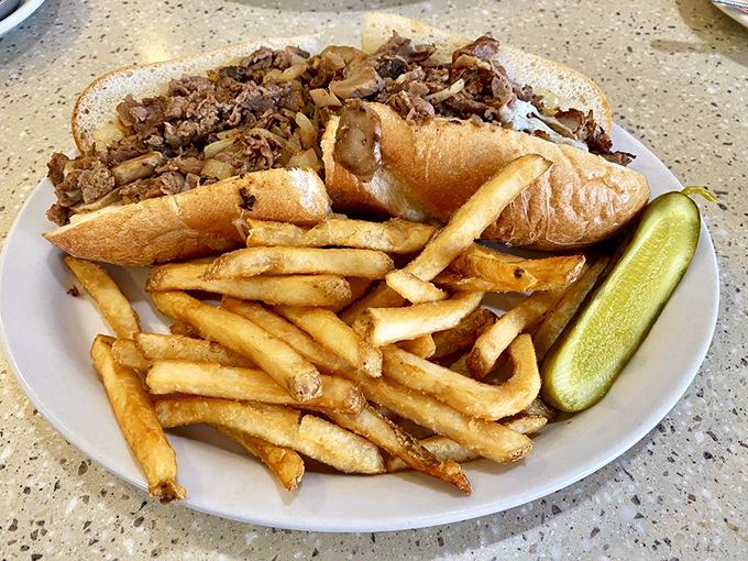 The Philly cheesesteak in its natural habitat: piled high on a roll with golden fries standing guard.