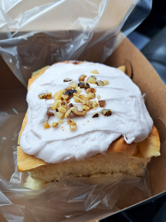 This isn't just a cinnamon roll; it's an edible pillow of happiness topped with cream cheese frosting and chopped nuts. Napkins required, regrets impossible.