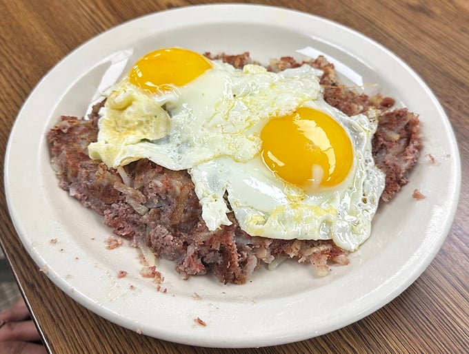 Corned beef hash crowned with sunny-side-up eggs—the breakfast equivalent of wearing a tiara. Pure diner royalty on a humble white plate.