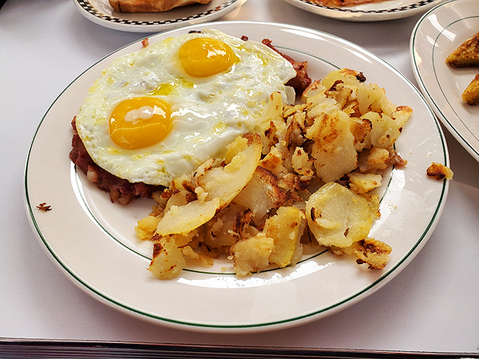 Two sunny-side-up eggs perched atop a mountain of home fries&mdash;proof that breakfast is the most important art form of the day.
