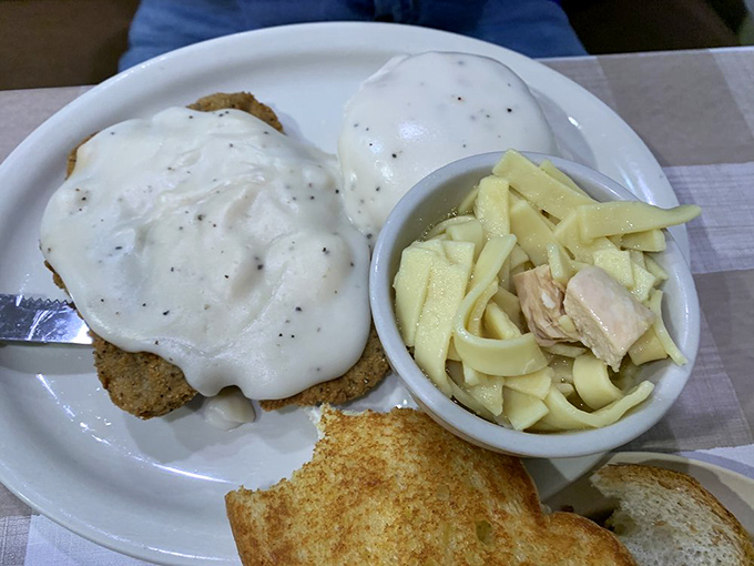 Country fried steak smothered in gravy alongside homemade noodles—proof that sometimes the most comforting foods are the ones that hug your plate.