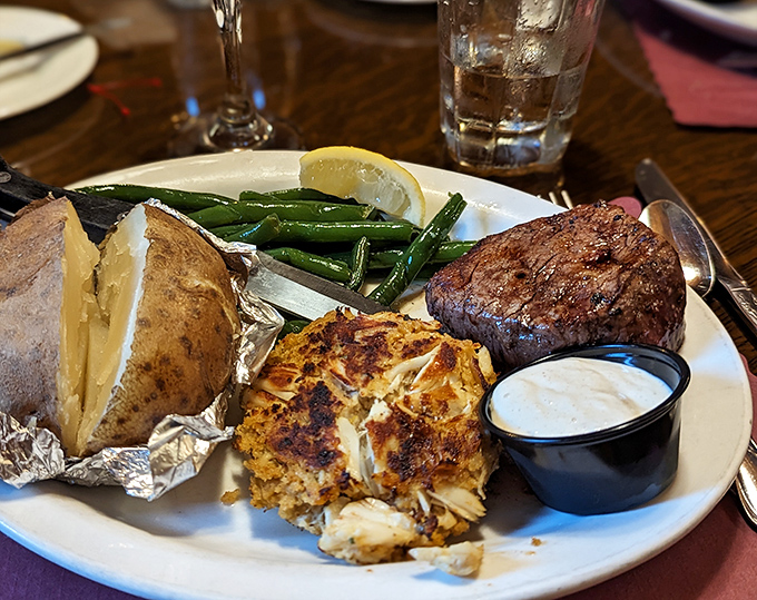 The surf meets turf in perfect harmony: a filet mignon, golden crab cake, and baked potato &ndash; the culinary equivalent of hitting the jackpot.