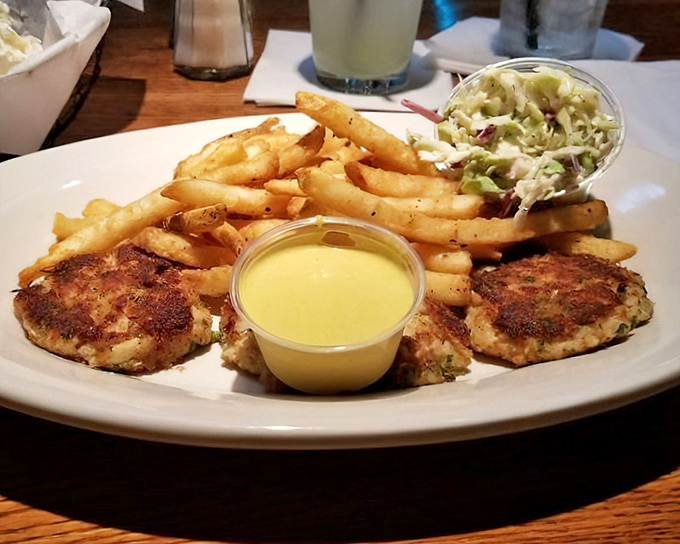 Golden-brown crab cakes with crispy exteriors hiding sweet, tender crabmeat within. The accompanying fries aren't just an afterthought.
