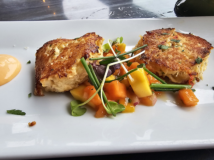 Golden-brown crab cakes that don't just sit on the plate—they perform, with colorful vegetables playing supporting roles in this culinary theater.