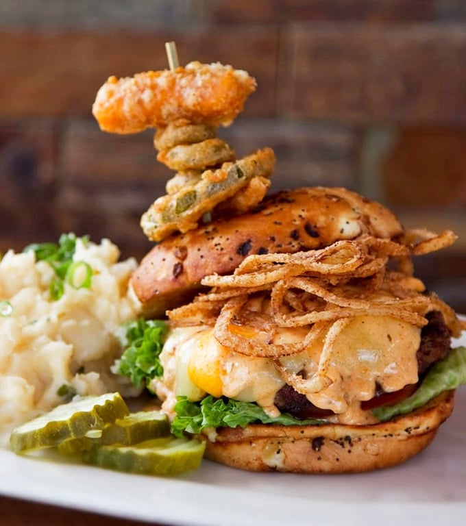 This isn't just a burger; it's an architectural masterpiece topped with crispy onions and a cheese curd skewer. Wisconsin engineering at its finest.