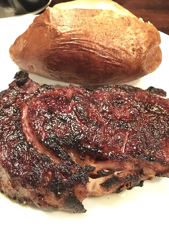 Behold the Delmonico with its glistening crust&mdash;this isn't just dinner, it's edible artwork. The potato stands by patiently, knowing its supporting role is crucial.