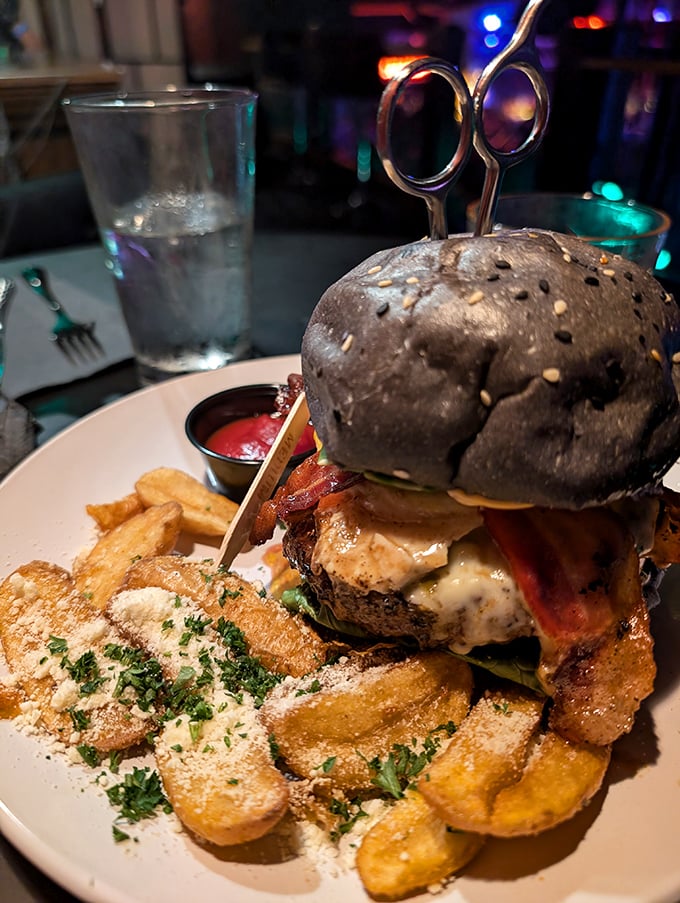 Not just a burger—a gothic tower of deliciousness with scissors stabbed dramatically into a black bun. Edward would be proud.