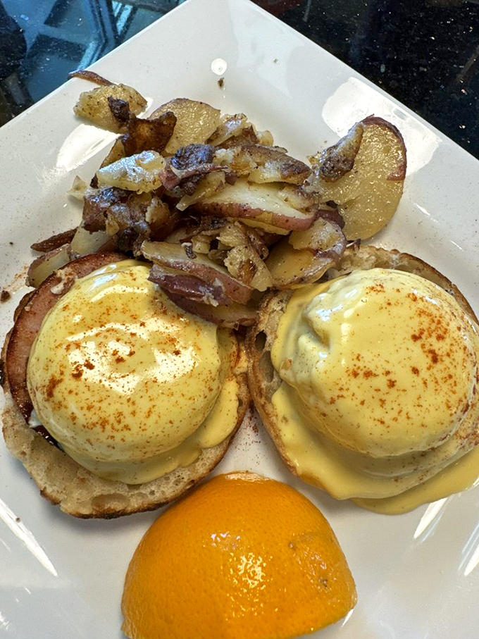 Perfectly poached eggs rest atop English muffins, drowning in hollandaise sauce that flows like sunshine.