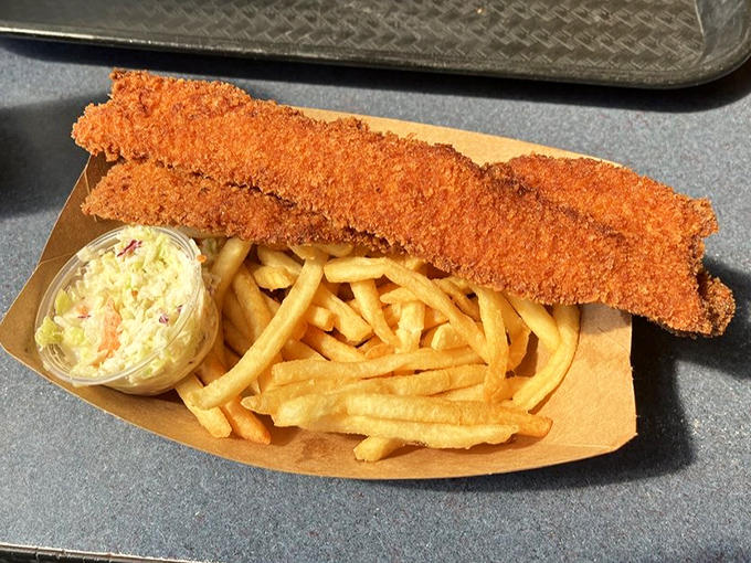 Golden-battered fish stretches across crispy fries like it's sunbathing on a delicious beach. Cole slaw adds that perfect tangy counterpoint to the crunch.