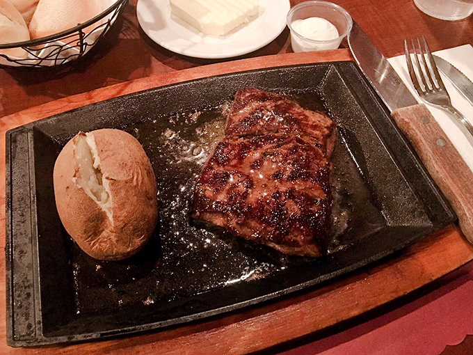 A steak sizzling on its own personal stage, accompanied by a baked potato understudy that's ready for its moment in the spotlight.