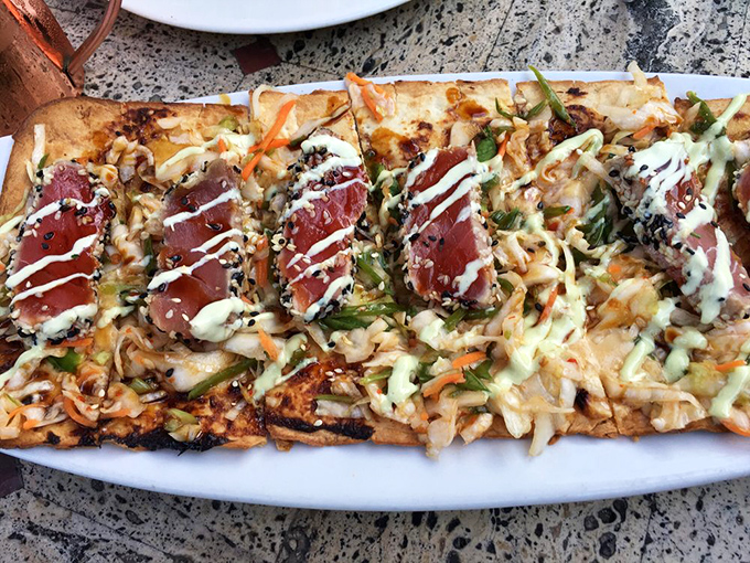 Flatbread that defies gravity - piled high with fresh ingredients and drizzled with sauce that zigzags like an artist's finishing touch.