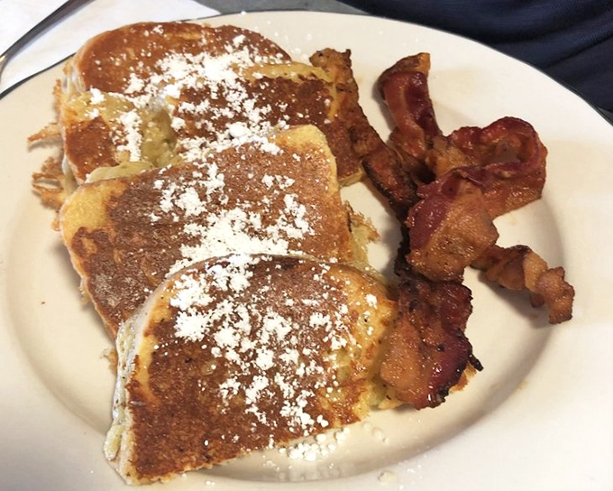 French toast dusted with powdered sugar alongside crispy bacon – the breakfast equivalent of having your cake and eating it too.