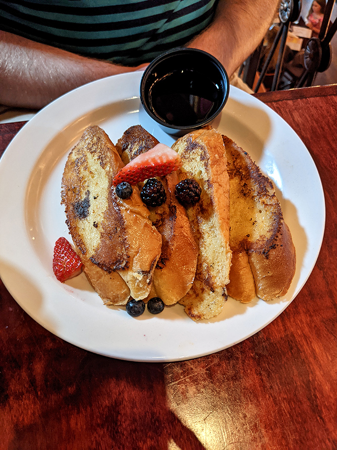 French toast that looks like it graduated from culinary school with honors. The syrup puddle is practically begging you to make questionable dipping decisions.