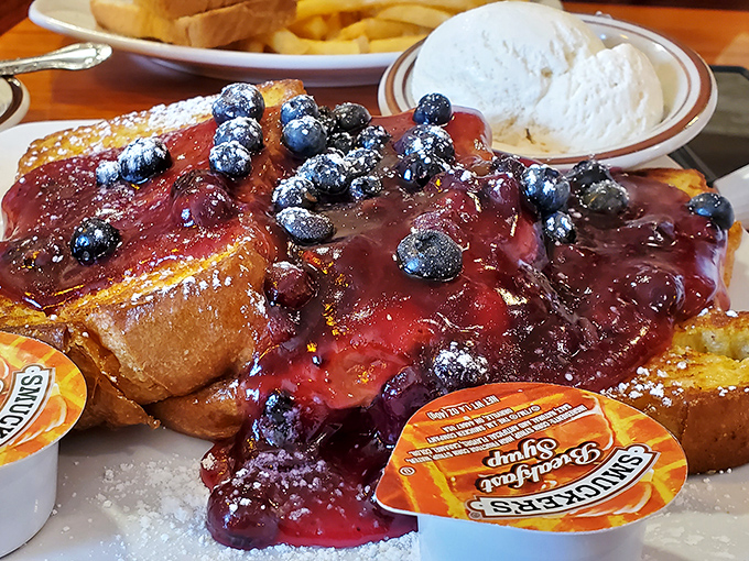 French toast that's having an identity crisis as a dessert &ndash; blueberry topping cascading down like sweet lava, with ice cream playing the perfect supporting role. 