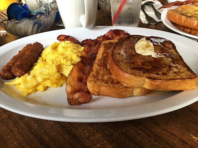 Breakfast perfection on a plate: golden French toast, fluffy scrambled eggs, and bacon that strikes that magical balance between crispy and chewy.