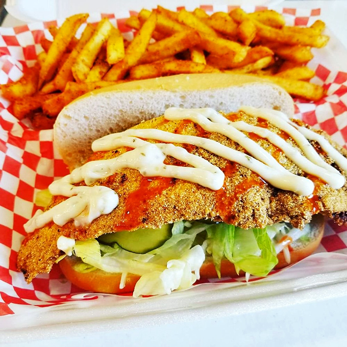A perfectly golden chicken sandwich with cooling slaw and ranch drizzle&mdash;proof that balance exists even in Nashville's fiery culinary universe. Those seasoned fries aren't just sides; they're essential equipment.