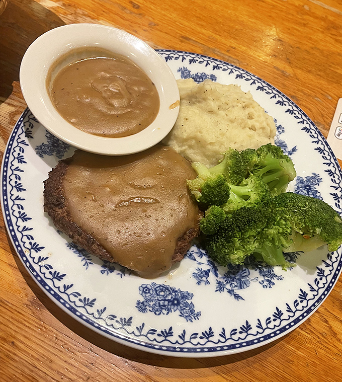 Country fried steak with gravy, mashed potatoes, and broccoli – the holy trinity of comfort food served on grandma's good china.
