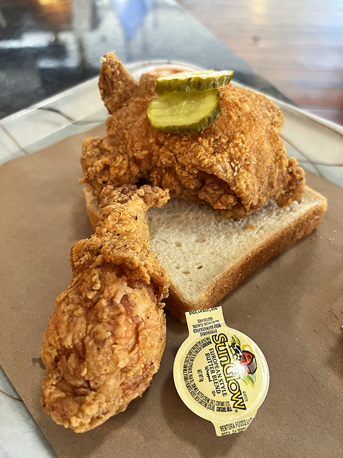 Fried chicken perched atop white bread with pickle chips standing guard. This isn't just a meal, it's a Southern tradition worthy of reverence.