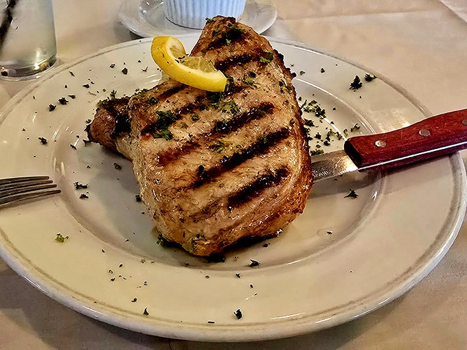 This isn't just a pork chop; it's a statement piece. Beautifully grilled, herb-dusted, and substantial enough to make vegetarians question their life choices.