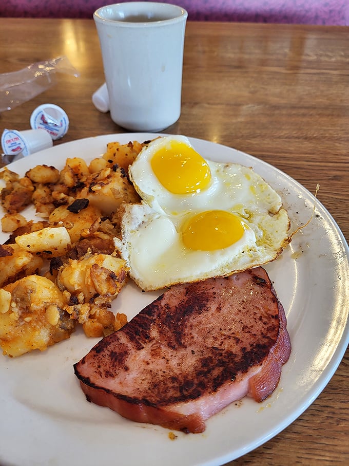 The holy trinity of breakfast perfection: sunny-side up eggs with yolks like liquid gold, crispy home fries, and ham seared to smoky perfection.