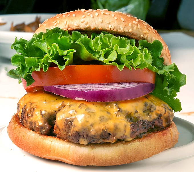 Behold the burger that launched a thousand return visits. The melted cheese cascades just so, while fresh veggies add the perfect crunch. Sesame seed bun as golden as childhood memories.