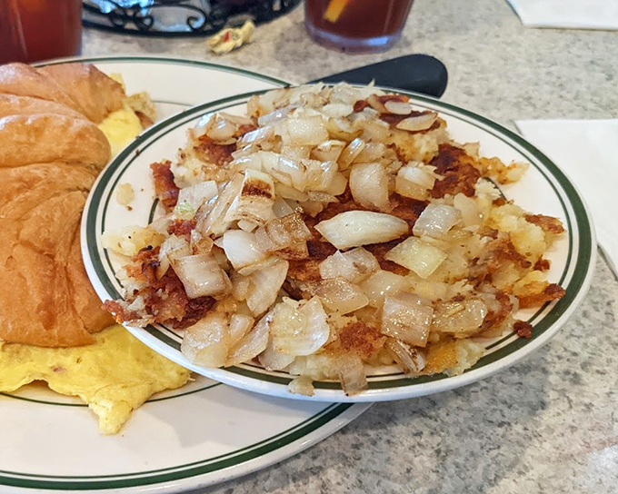 Golden home fries that crackle with each bite, topped with perfectly sautéed onions—the kind of breakfast side that makes you question why anyone would choose toast.