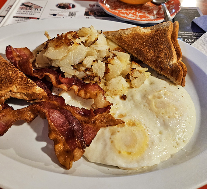 This isn't just breakfast – it's edible nostalgia. Crispy bacon, perfectly fried eggs, and home fries that deserve their own fan club.