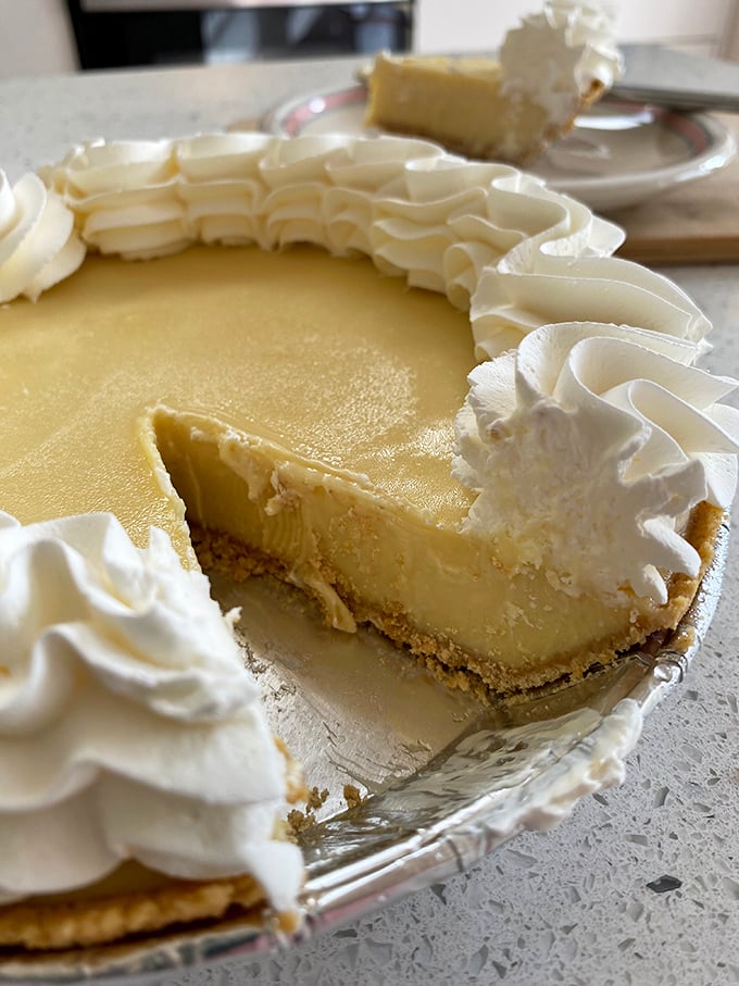 The perfect slice reveals the holy trinity of key lime pie: creamy yellow filling, buttery graham cracker crust, and a crown of whipped cream.