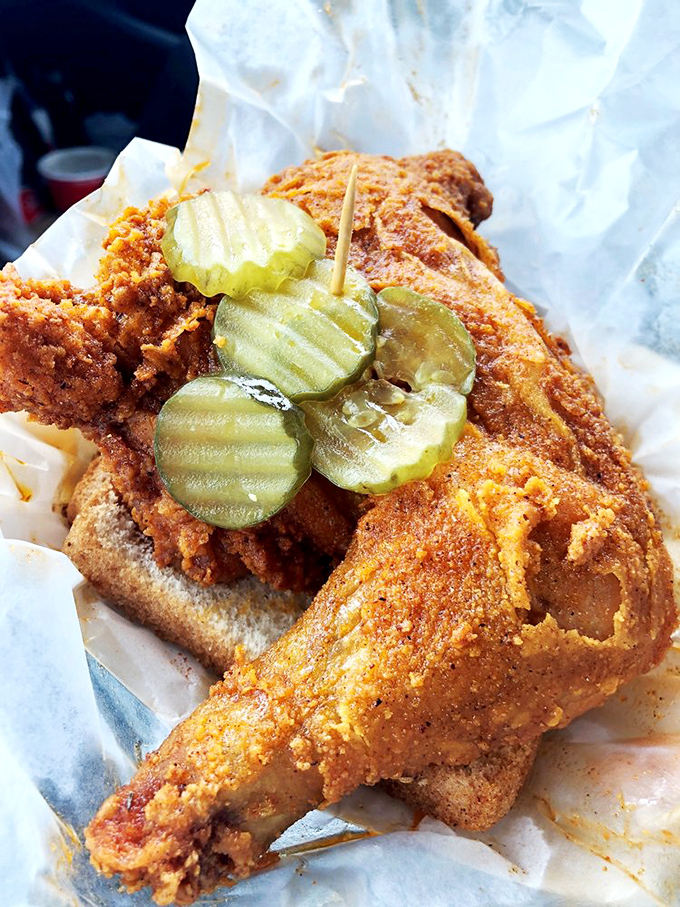 The perfect hot chicken specimen: crispy, ruddy exterior giving way to juicy meat beneath. Those pickles are the life rafts in a sea of spice.