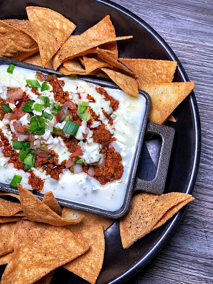This isn't your ballpark nacho situation. The melty cheese bath with bacon crumbles transforms triangular chips into vehicles of pure joy.
