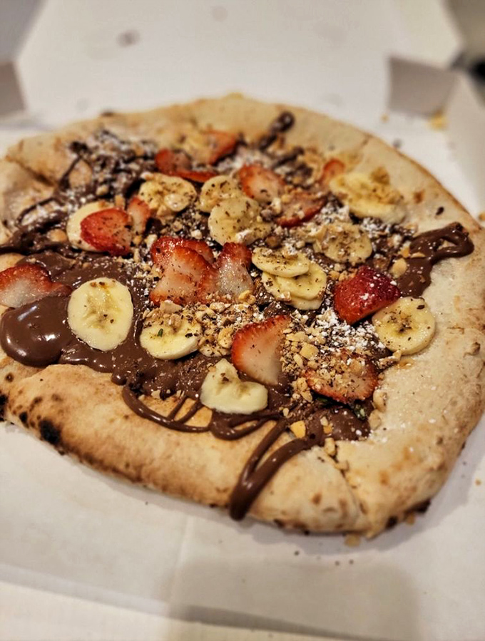 Dessert pizza that would make even the strictest Italian nonna smile. Nutella, bananas, and strawberries on that perfect charred crust? Genius!