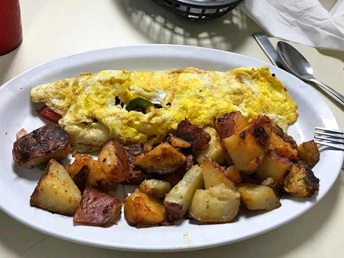 The holy trinity of breakfast perfection: a golden omelet that's somehow both fluffy and substantial, alongside home fries with that ideal crispy-to-tender ratio.
