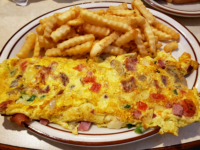 An omelet that's seen more fillings than a dentist's office, paired with fries crispy enough to make a potato proud.