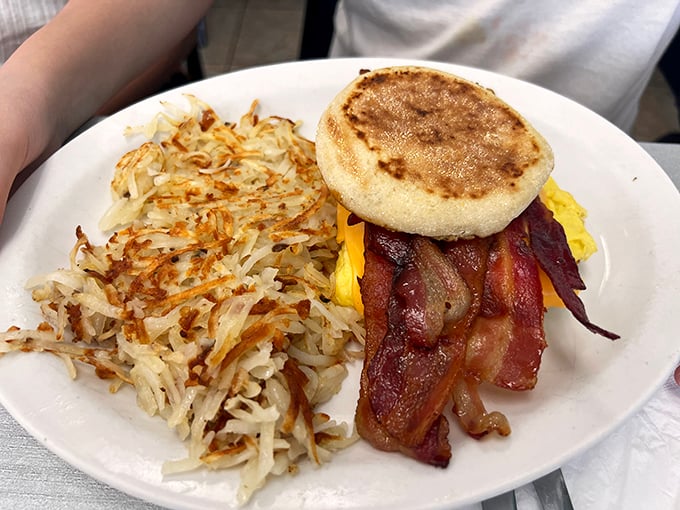 Breakfast architecture at its finest &ndash; crispy hash browns, perfectly cooked bacon, and a golden English muffin creating the holy trinity of morning satisfaction.