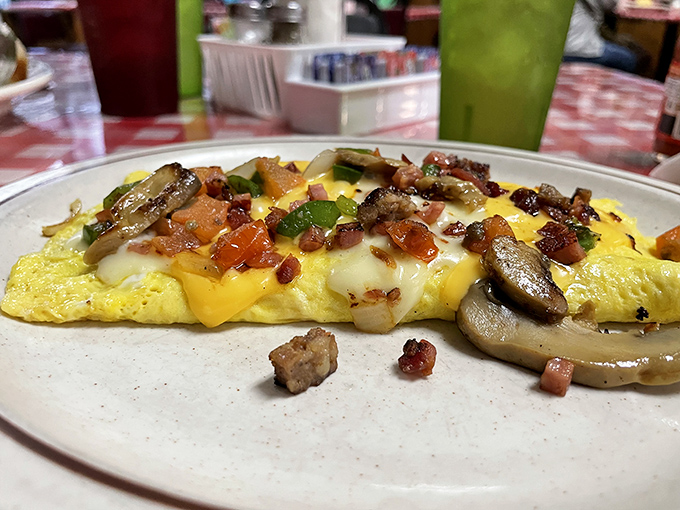 This isn't just an omelet—it's an architectural marvel of perfectly folded eggs cradling a treasure trove of mushrooms, peppers, and cheese that stretches with each bite.