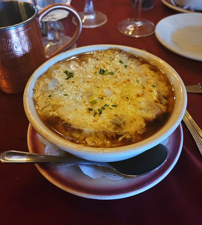 French onion soup with a cheese pull that deserves an Olympic medal. Beneath that golden canopy lies a savory treasure worth diving for.