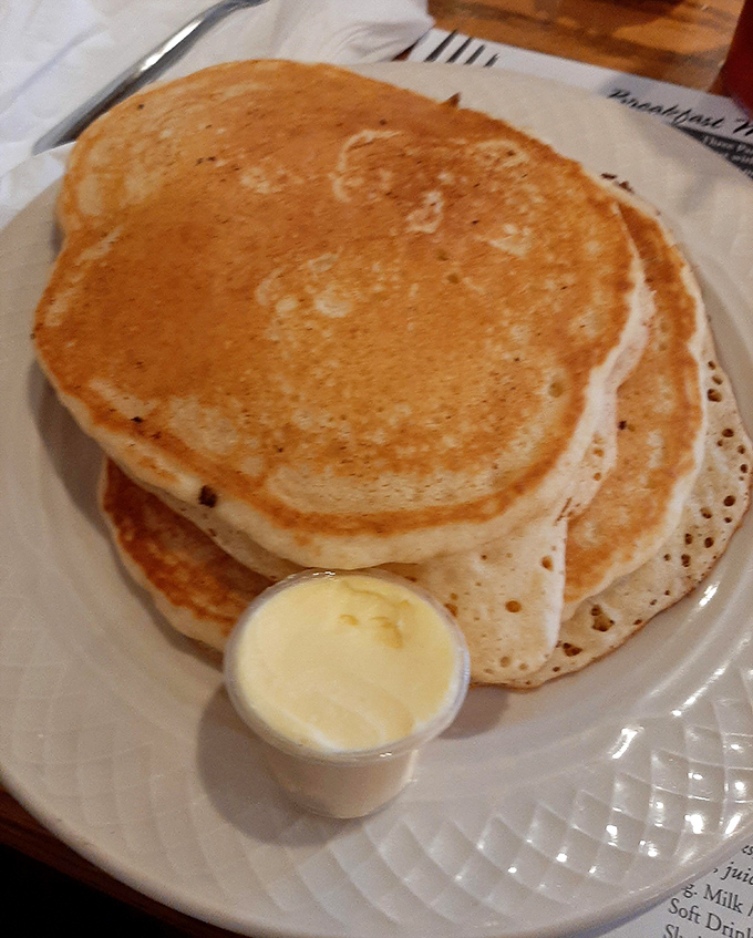 Golden-brown pancakes stacked higher than your weekend expectations. The butter cup stands by, ready for its moment of melty glory.