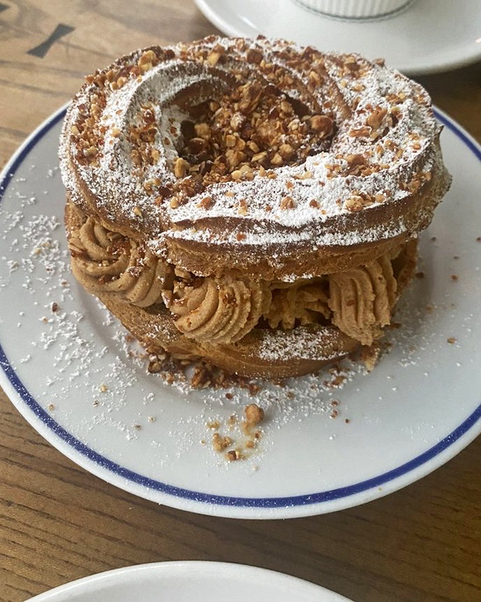 This Paris-Brest isn't just dessert, it's architecture. Delicate choux pastry filled with praline cream and dusted with powdered sugar creates a monument to French pastry prowess.