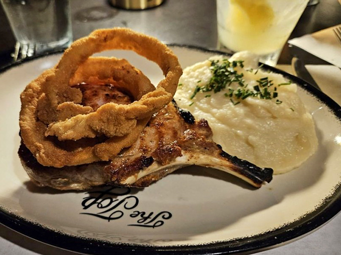 That pork chop isn't just dinner, it's architecture&mdash;towering over creamy potatoes with crispy onion rings as its crown. Savory skyscraper.